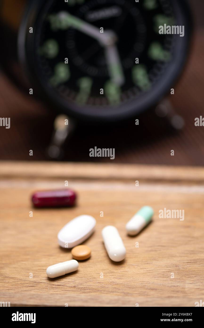 Alarm clock and medication pills on wooden tray for daily routine Stock ...