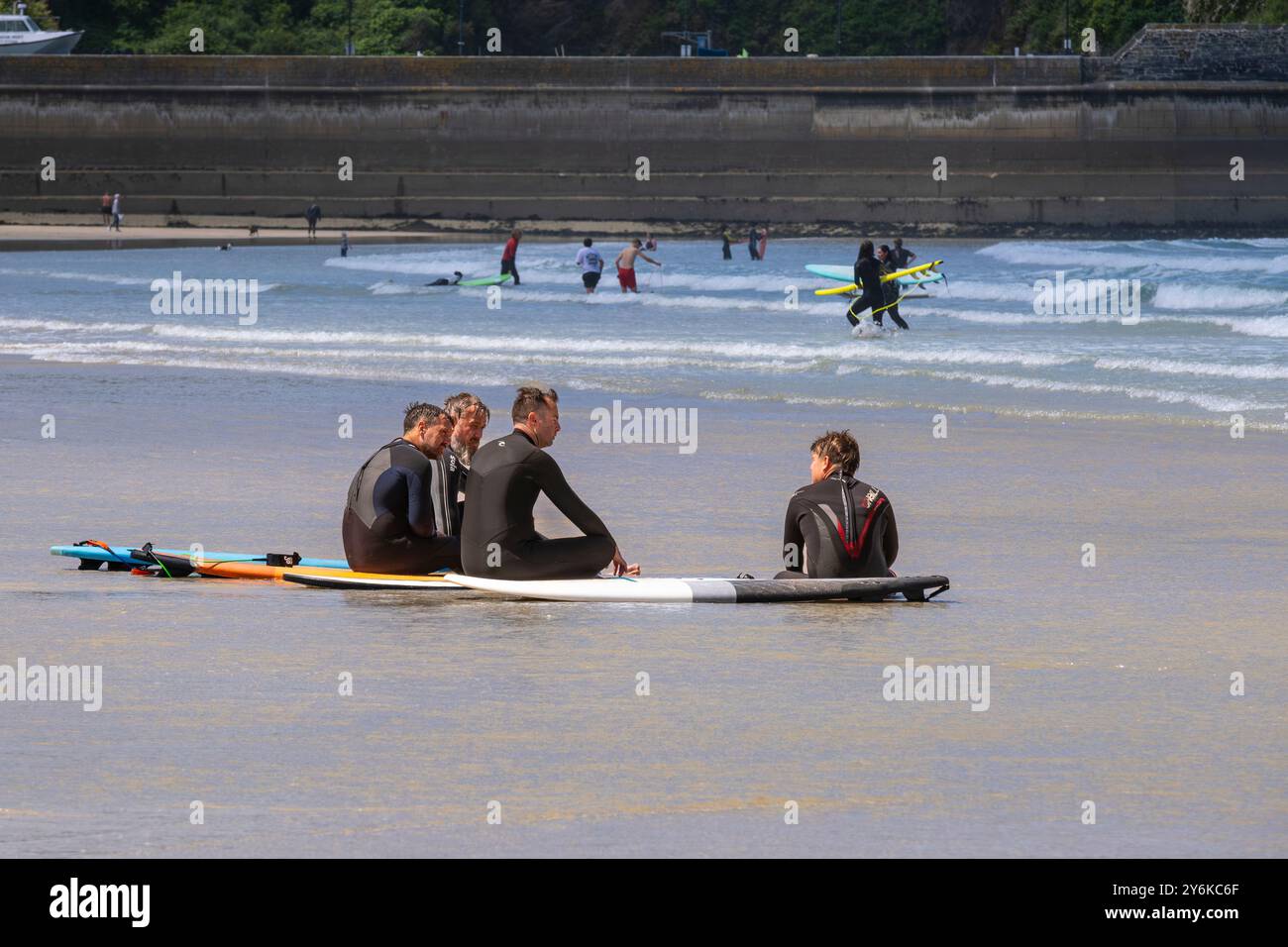 A group of mature male surfers sitting on their surfboard on the shore ...