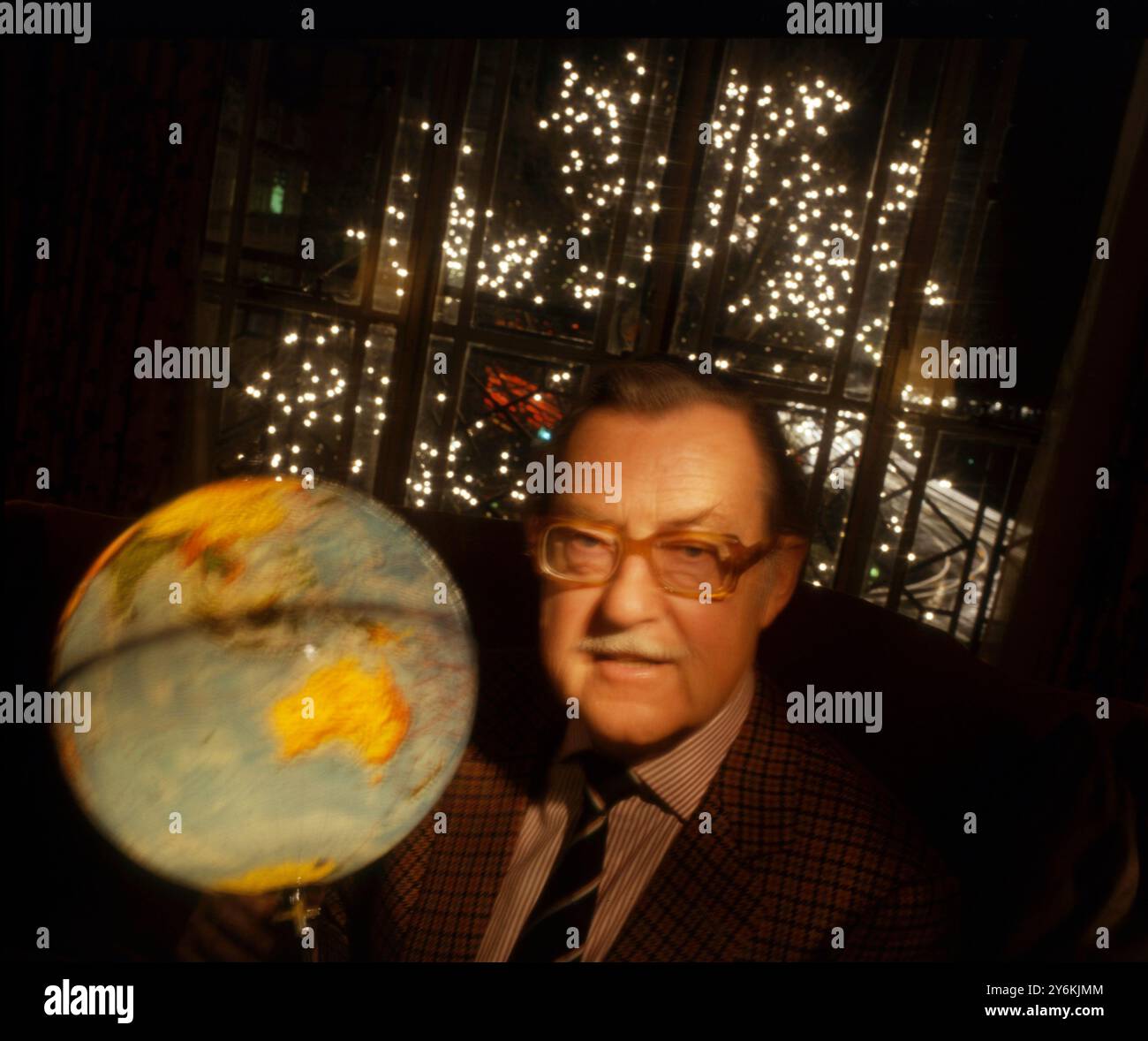 Portrait of British journalist Alan Whicker holding a globe in London ...