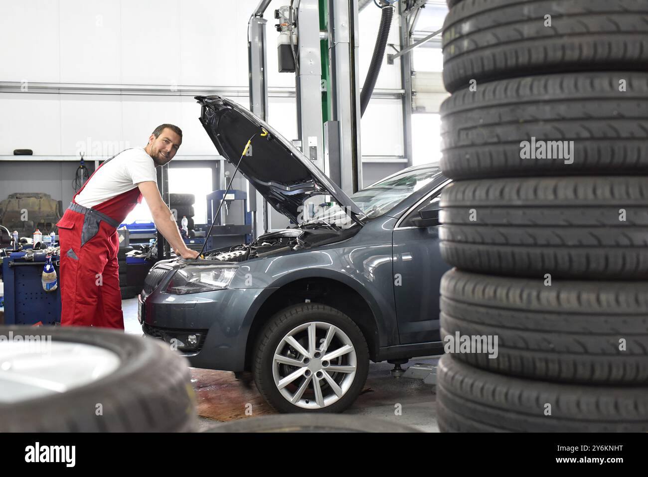 car mechanic in work clothes works in a workshop and repairs a vehicle ...
