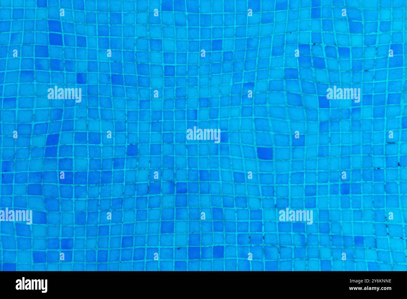 pattern of blue pool tiles under water with textured water surface ...