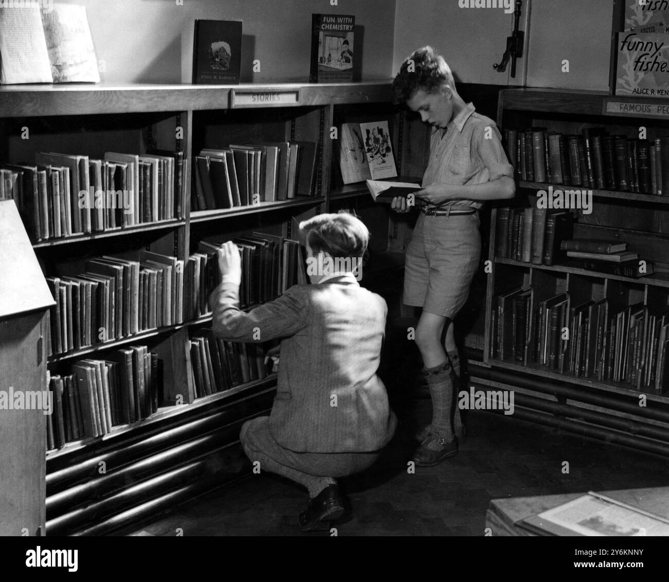 Two boys choosing books in a library Stock Photo - Alamy