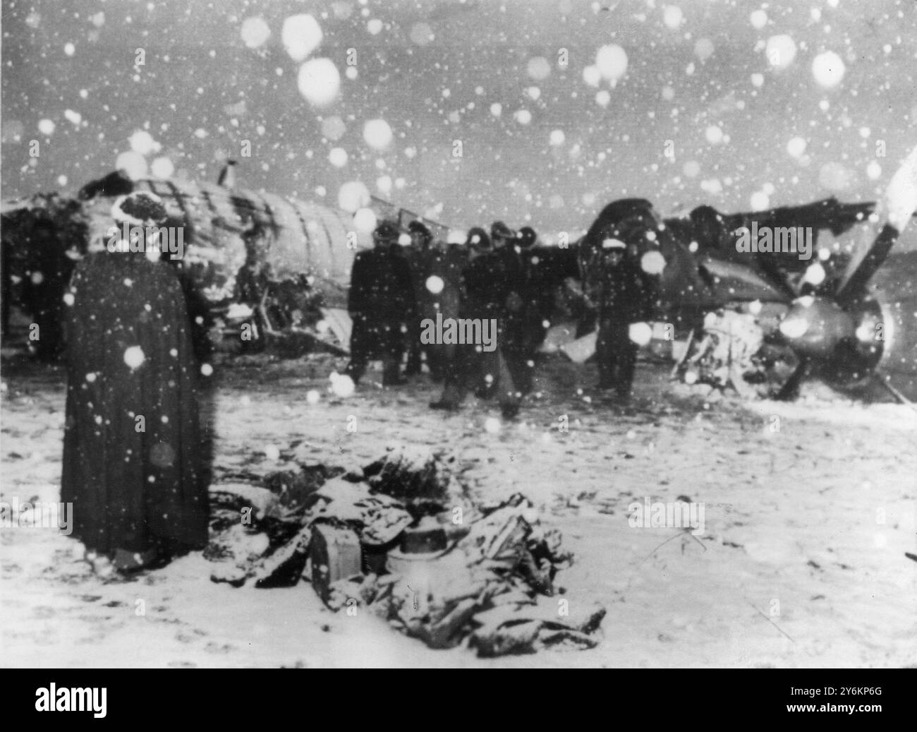 Rescuers and officials cluster round the wreckage lie in the snow after ...