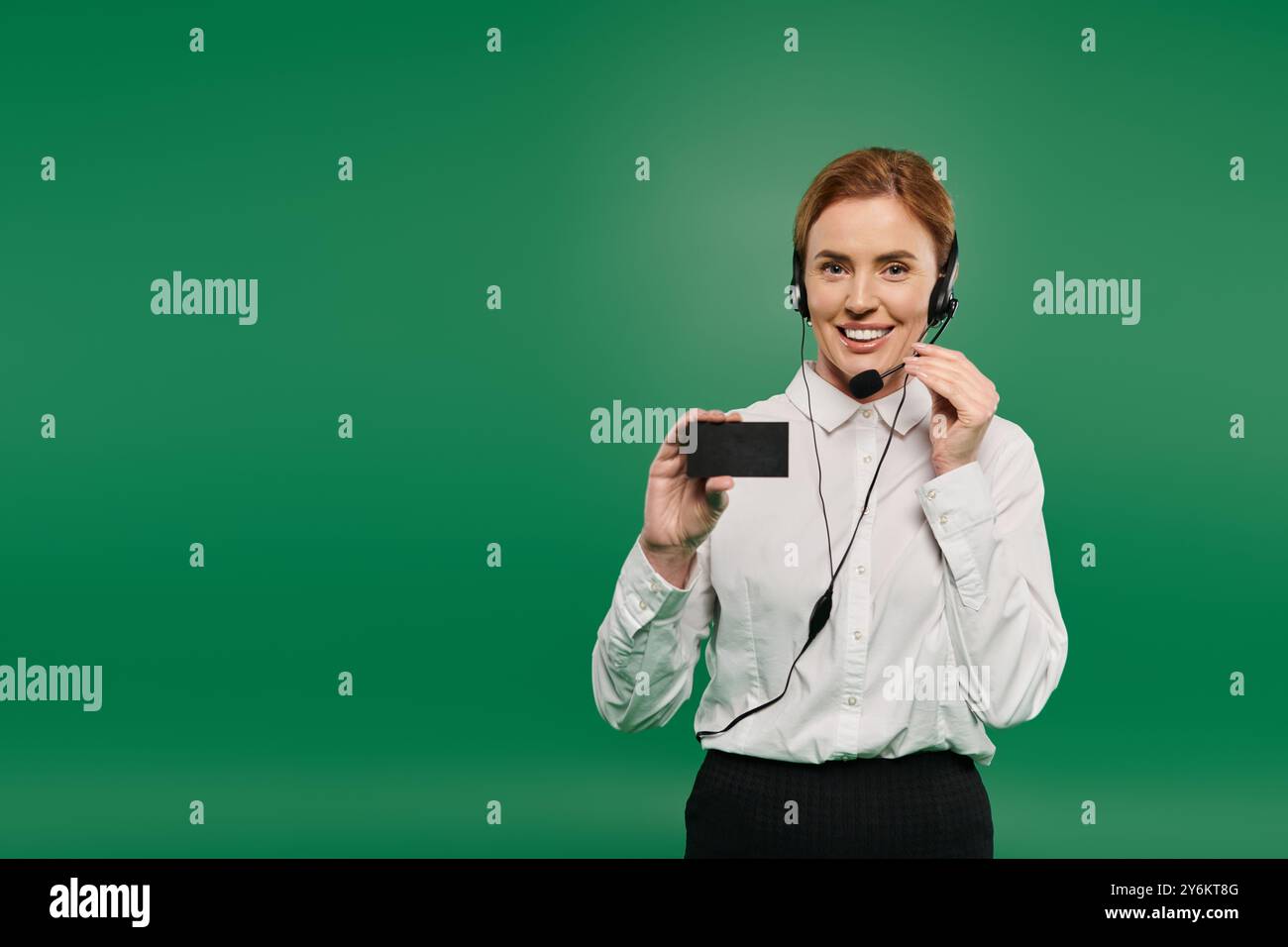 A confident woman in a white shirt smiles while holding a device, ready ...