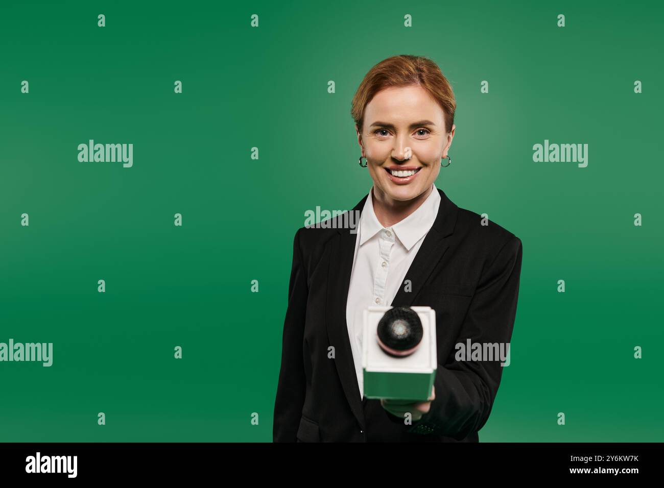A confident TV presenter in elegant black attire stands on a vibrant ...