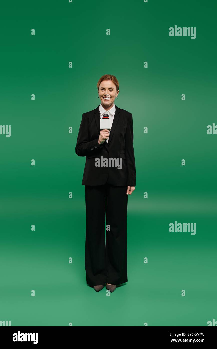 A confident TV presenter engages the audience in black formal wear, set ...
