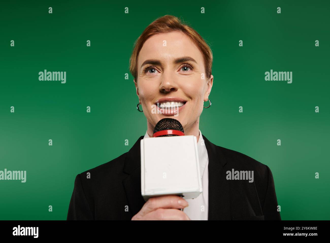 A TV presenter stands poised with a microphone, showcasing a stylish ...