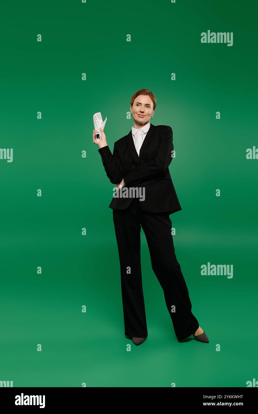 A poised TV presenter stands against a bright green backdrop Stock ...