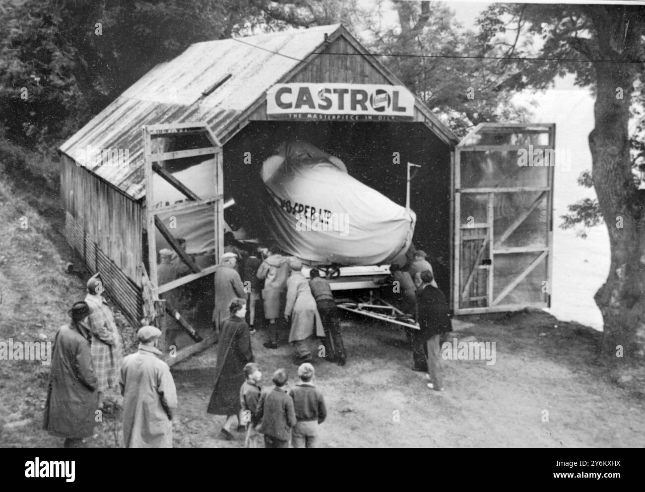 John Cobb wearing cap in foreground, watches jet propelled speedboat ...