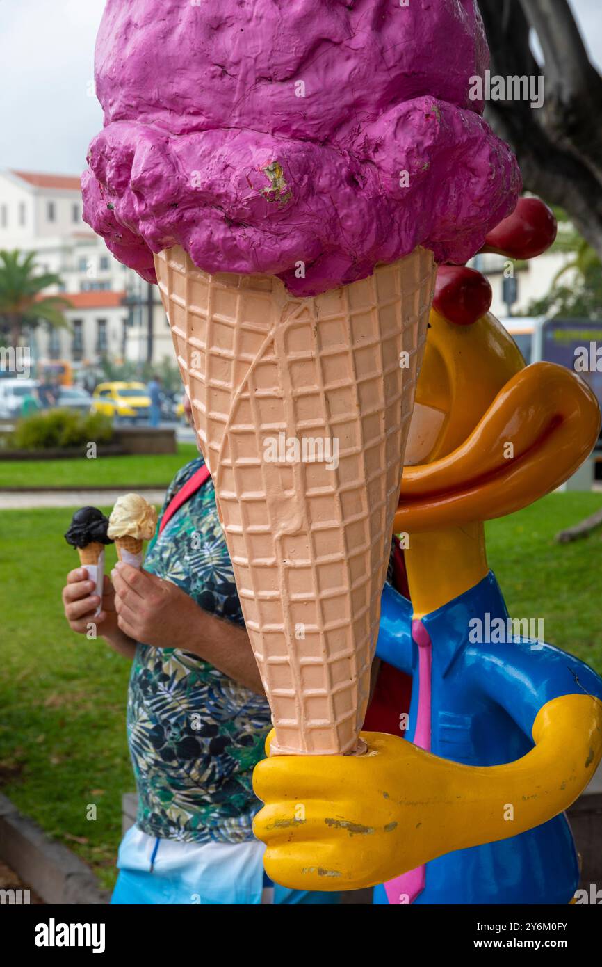 Man with two ice cream cones behind a display of an ice cream shop ...