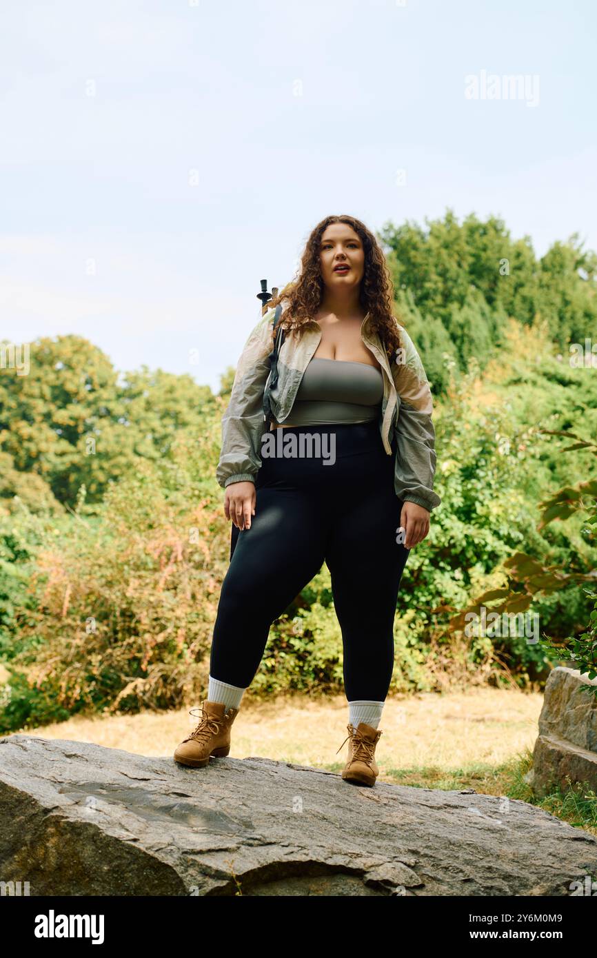 A confident plus size woman stands proudly on a rock, surrounded by ...