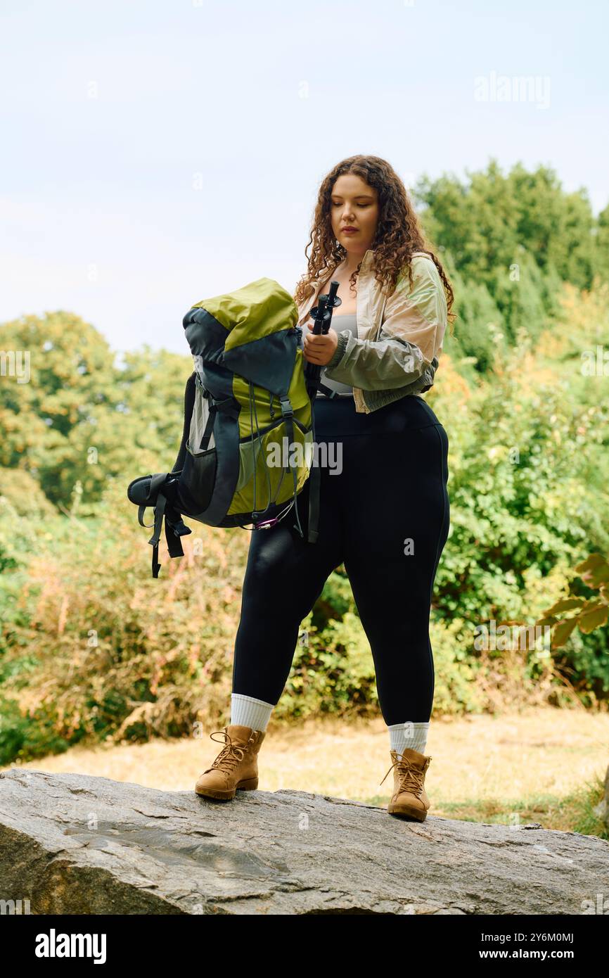 A confident plus size woman stands amid lush greenery, getting ready ...