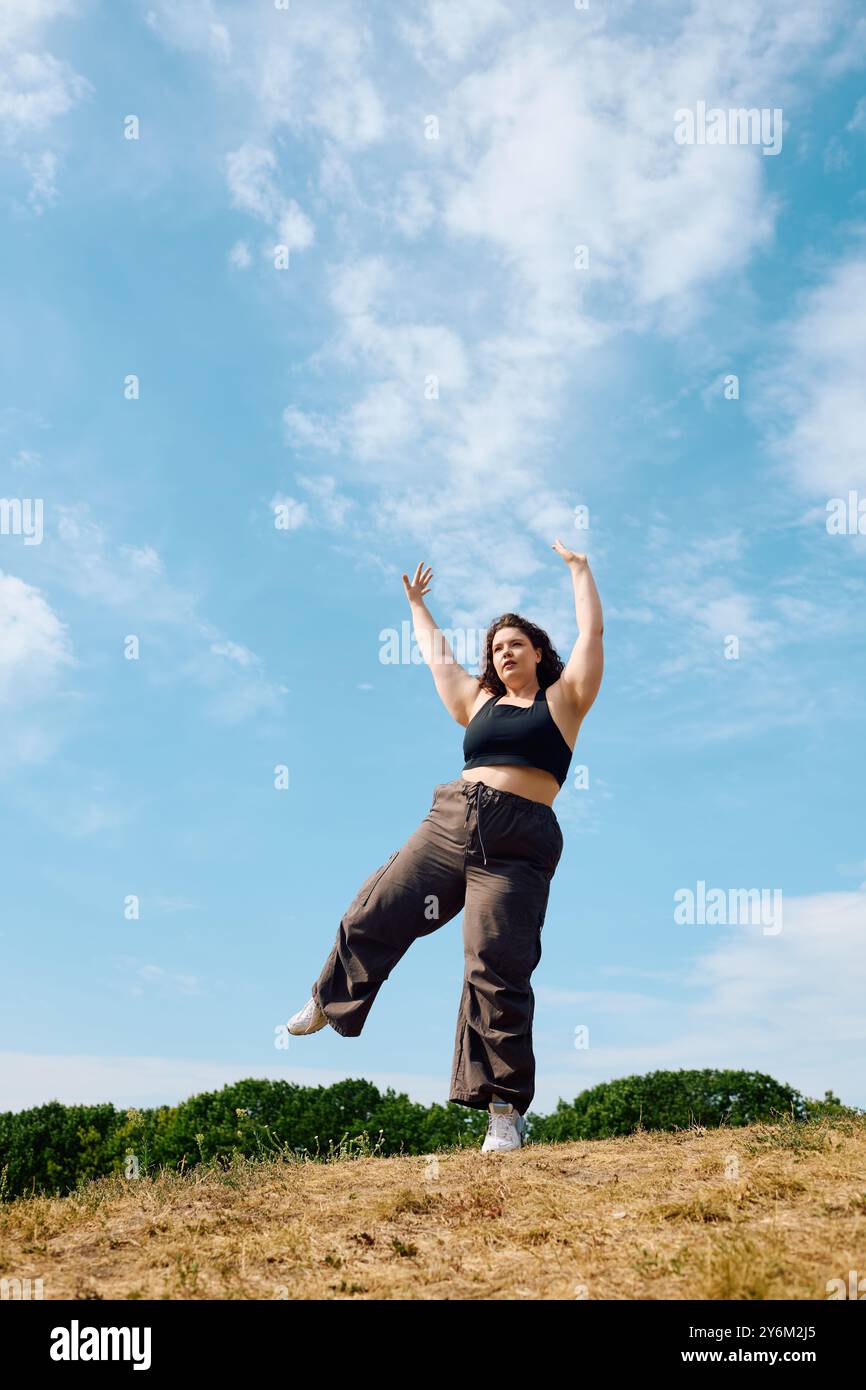 A joyful plus size woman dances freely in a vibrant field under a ...