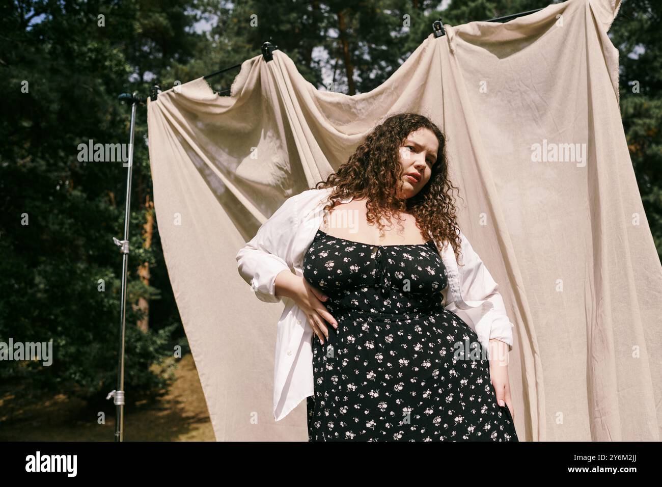 A confident plus size woman poses gracefully among lush greenery and ...