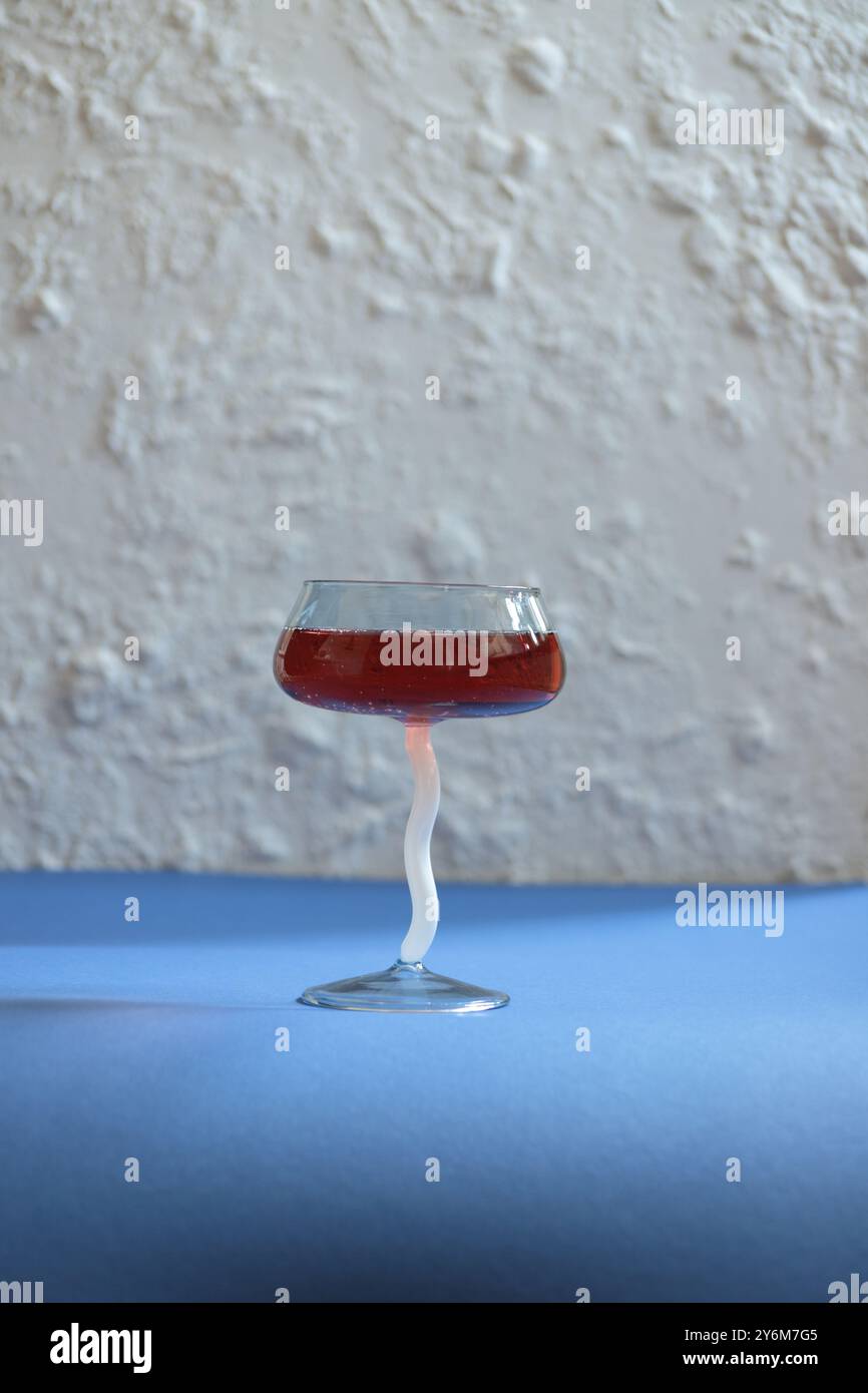 Elegant burgundy cocktail presented in a white wavy stem glass ...
