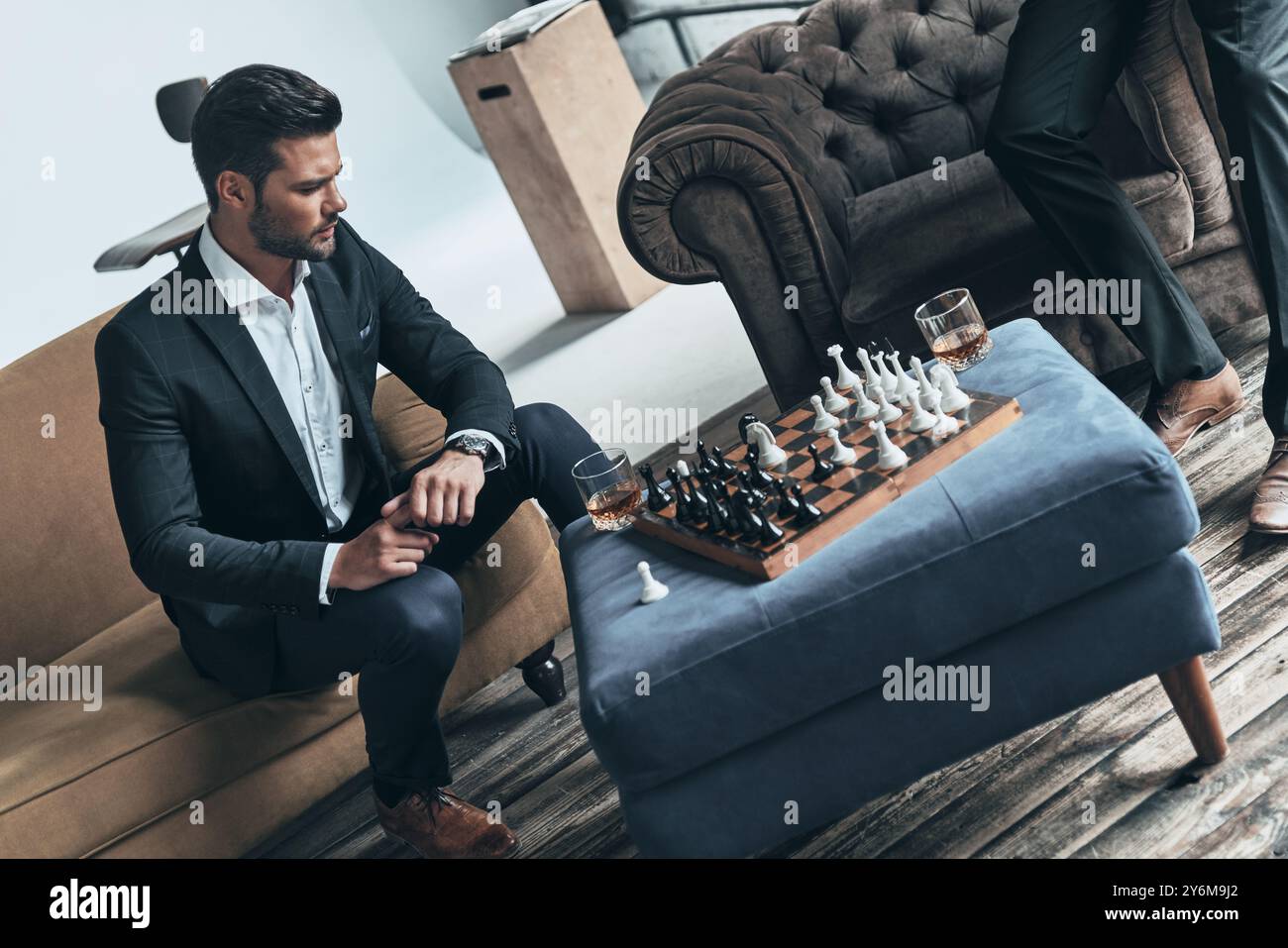 Think good. Young thoughtful man in full suit playing chess while ...