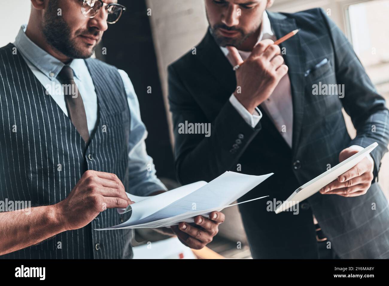 Working with documents. Two young modern men in formalwear working ...