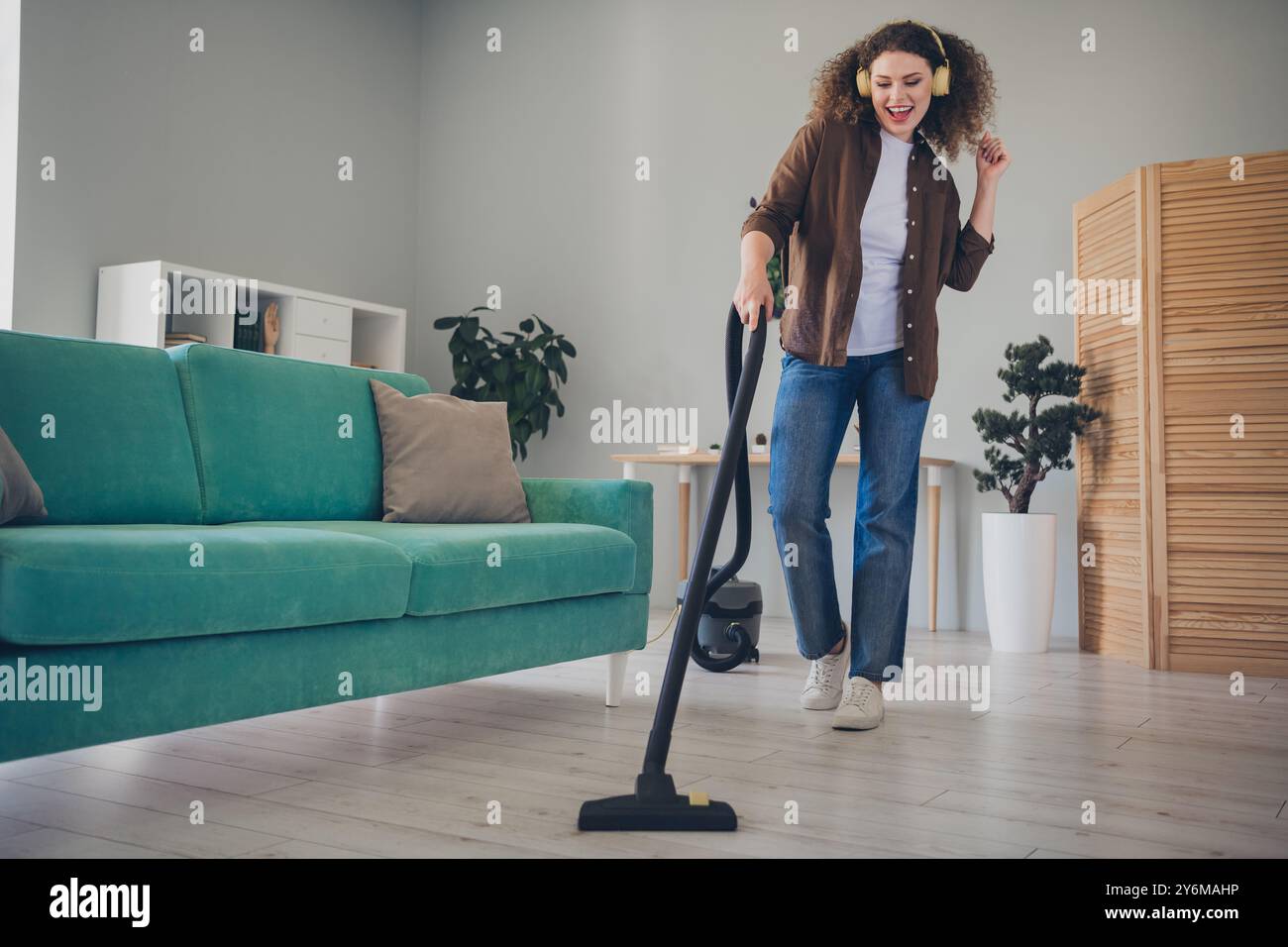 Photo of charming lady using vacuum cleaner for floor dust at her new ...