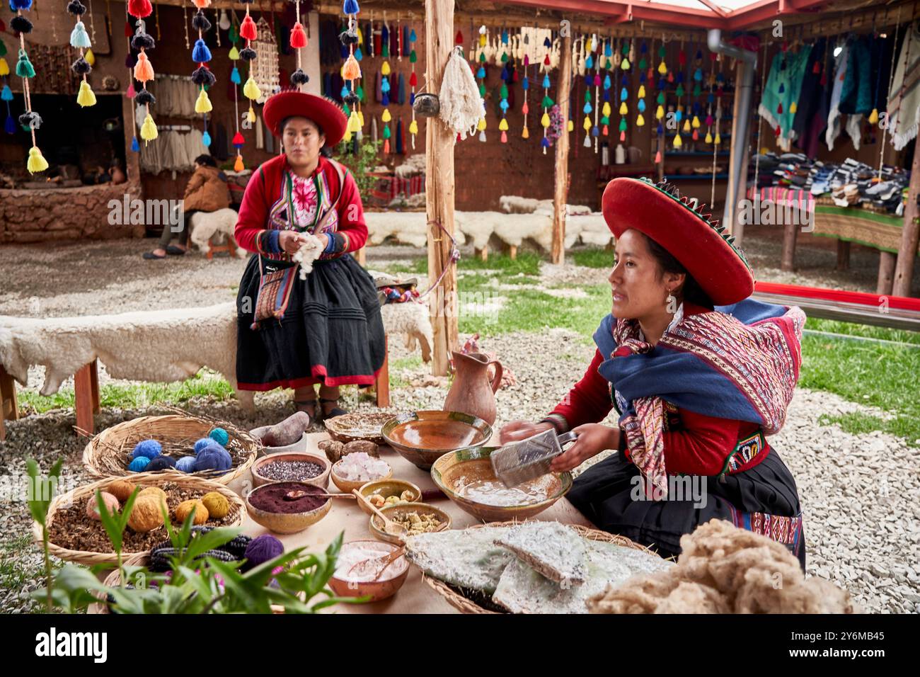 Two women in traditional Andean attire showcase the art of weaving in a ...