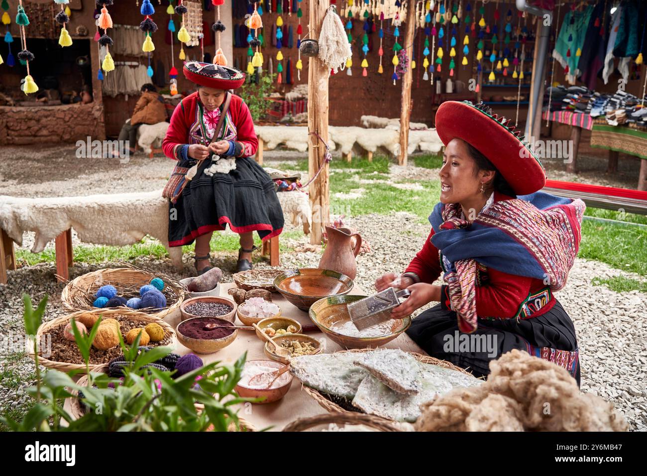 Two women in traditional Peruvian attire craft textiles at a vibrant ...