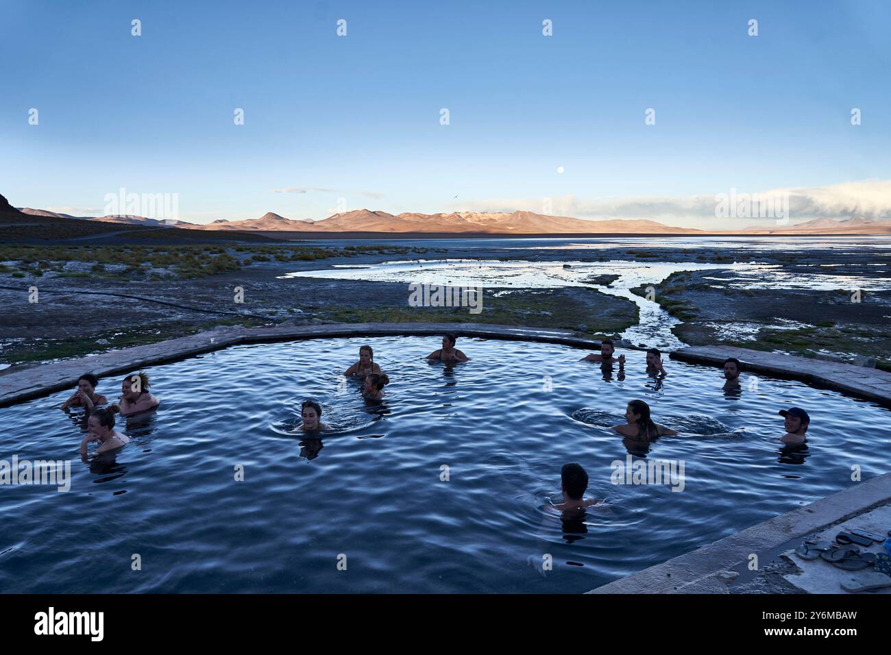A group of people relax and unwind in a natural hot spring surrounded ...