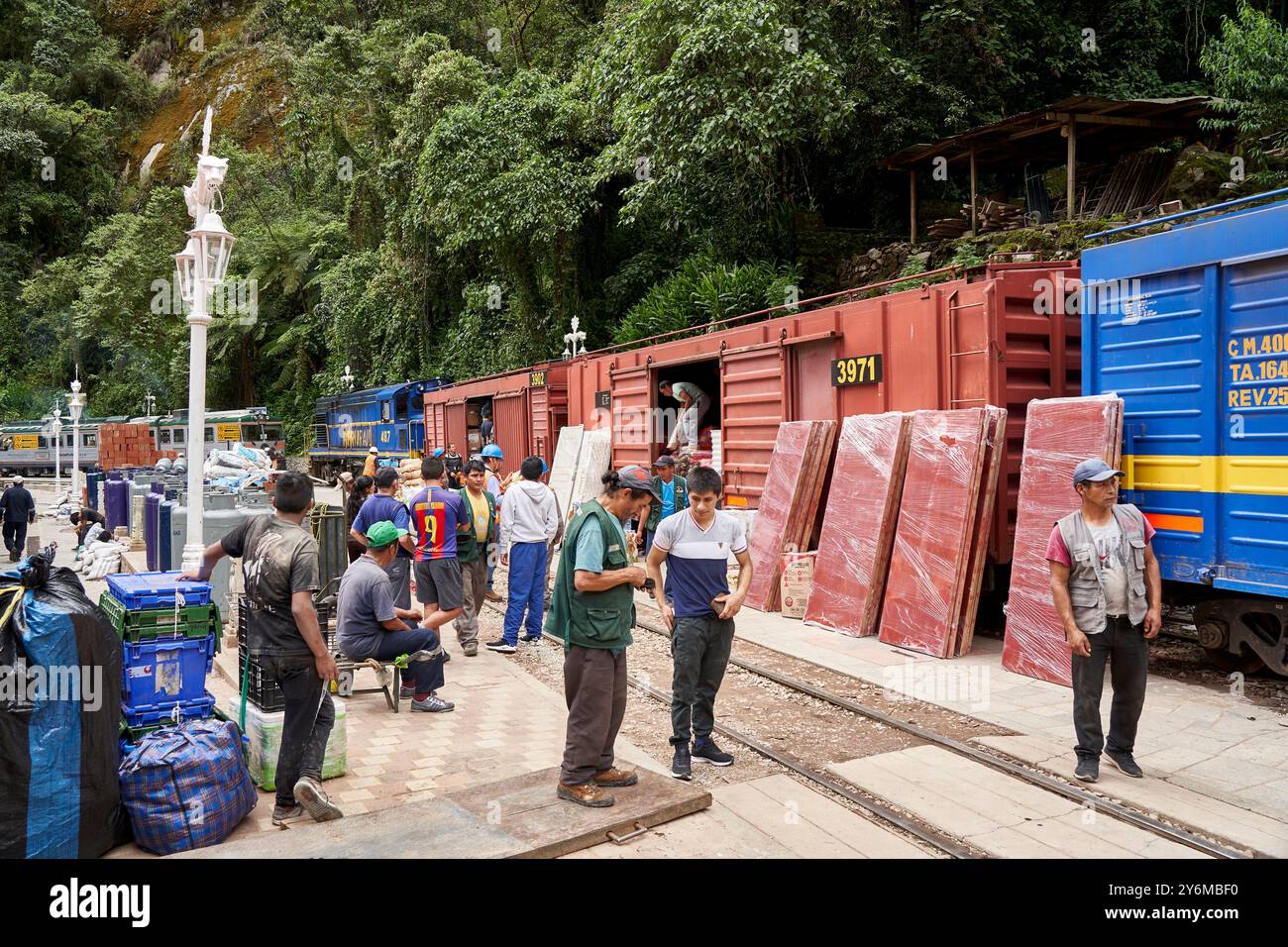 A group of workers busy unloading packages from a train at the Machu ...