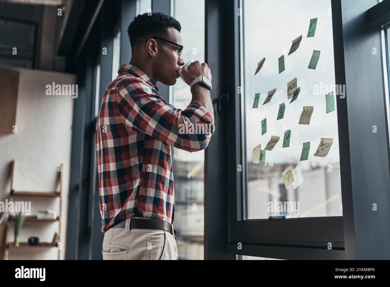 Planning his business. Serious young man applying adhesive notes to ...
