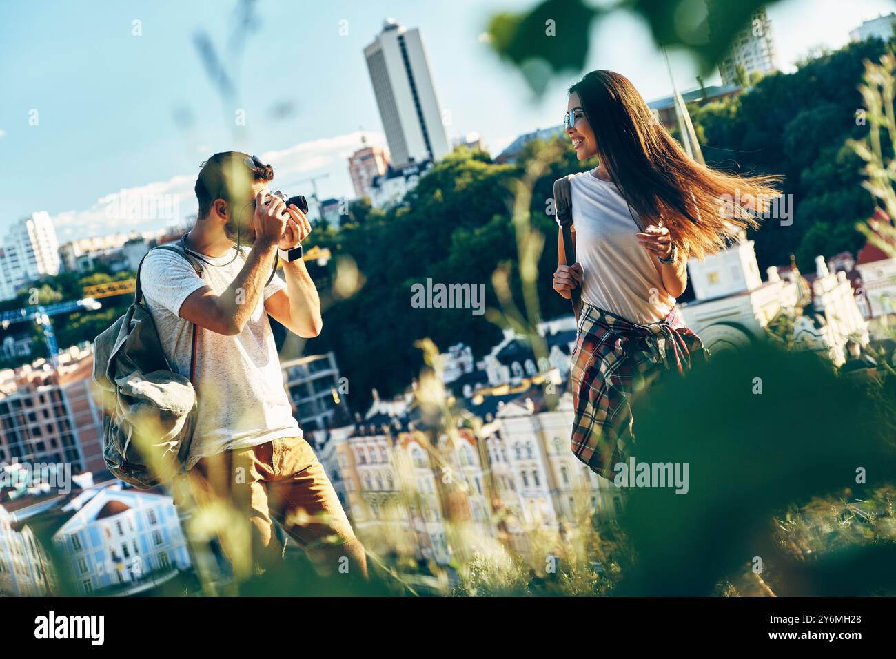 Young man photographing his girlfriend while standing on the top of the ...