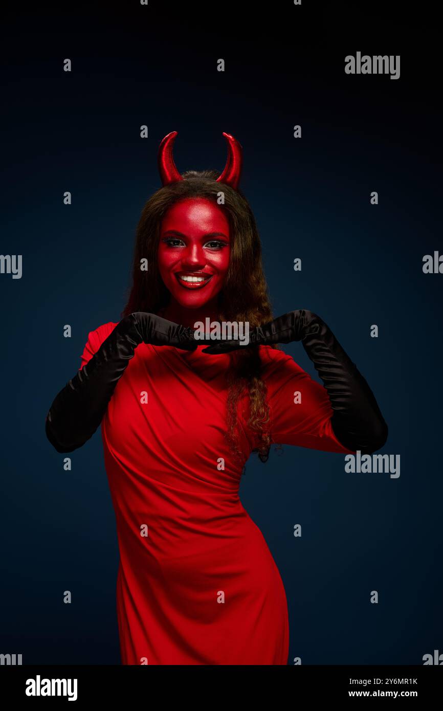 This striking woman in a red devil costume playfully poses, showcasing ...