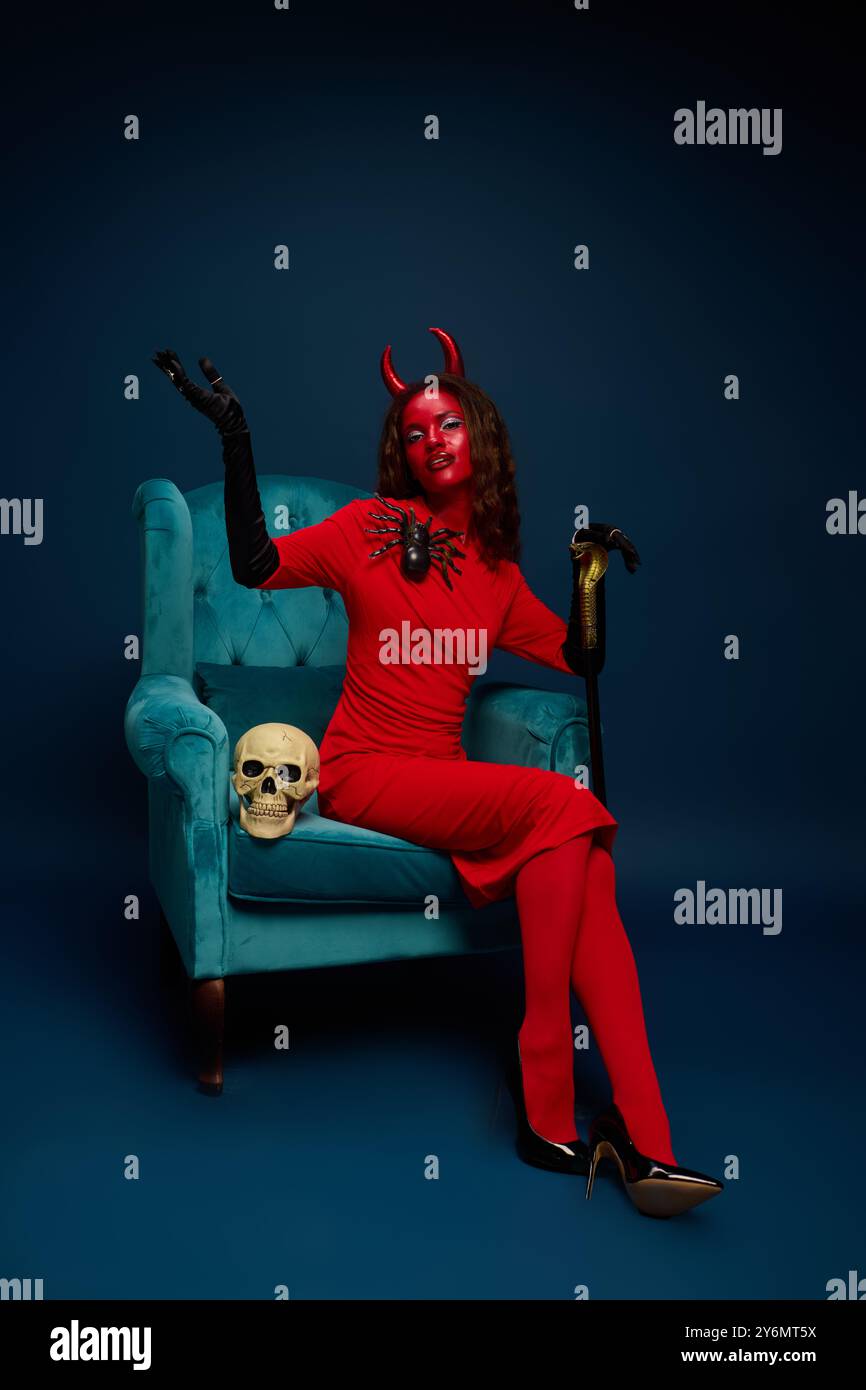 A stunning woman in a devil outfit confidently sits in a chic turquoise ...