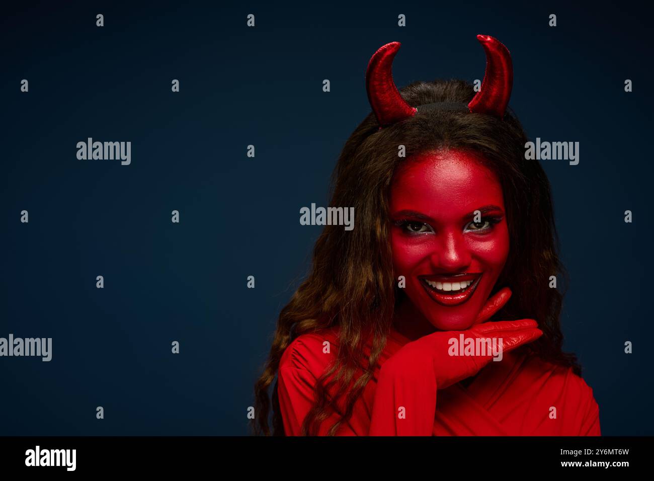 A striking woman dressed as a devil showcases her playful spirit with a ...