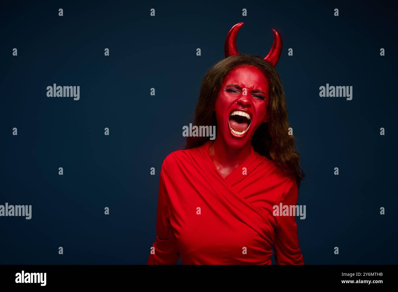 A woman in stunning red attire channels her inner devil, expressing ...