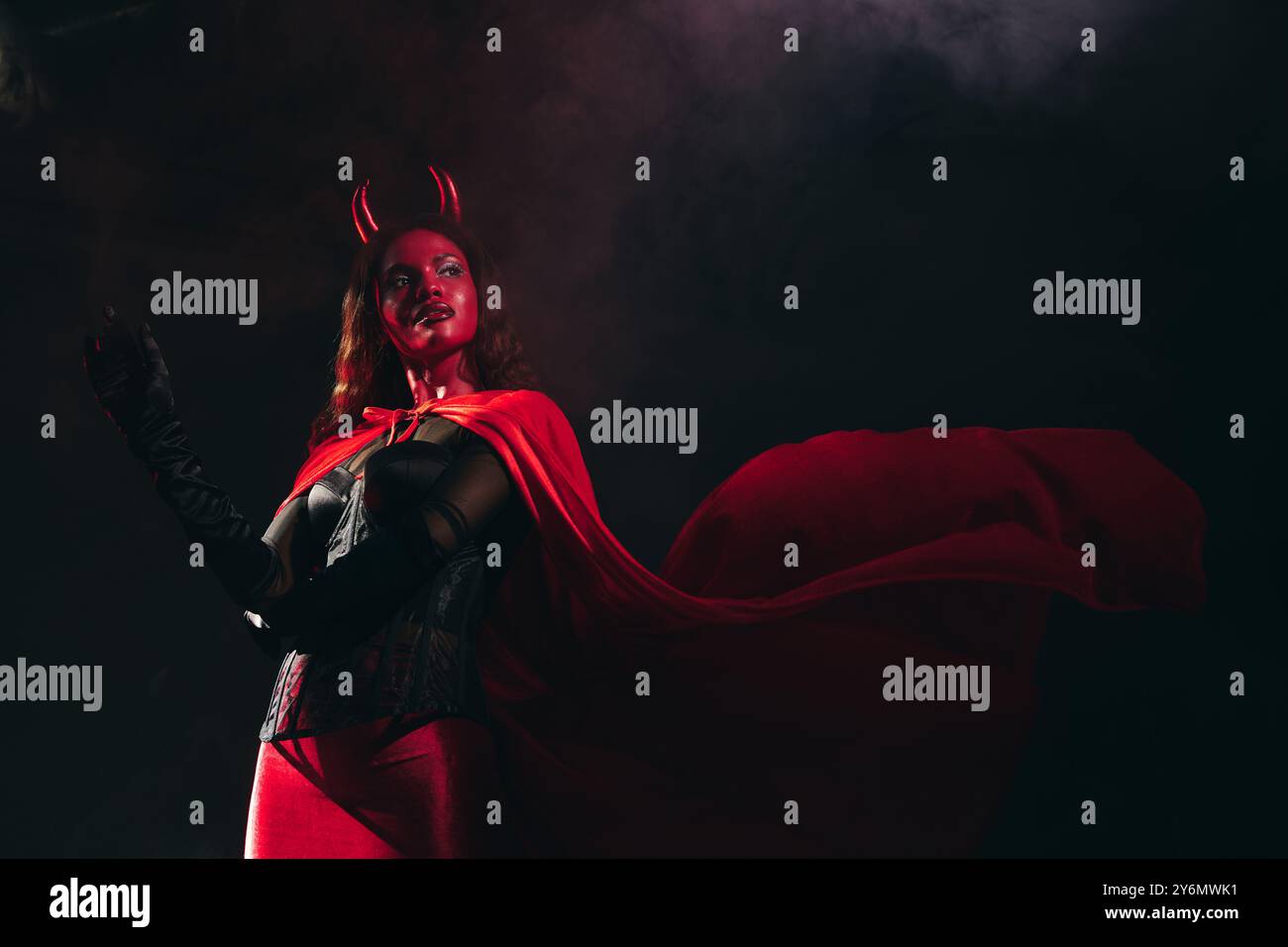 A stunning woman in a devil costume poses, radiating Halloween spirit ...