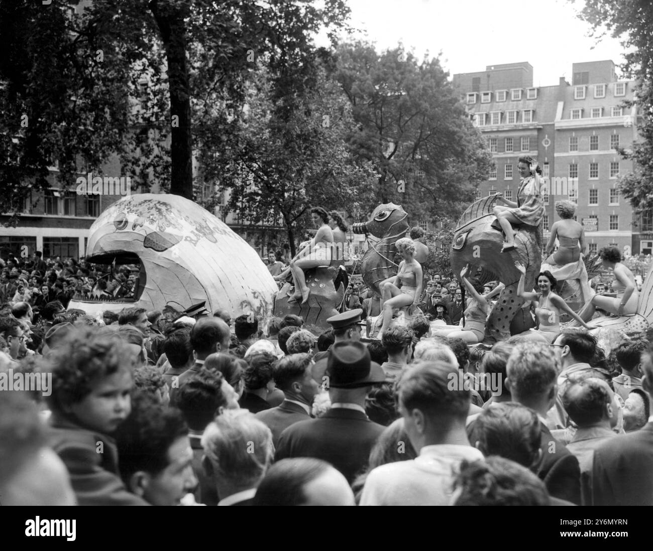 Girls in swimsuits ride on a float through crowded Soho Square during ...