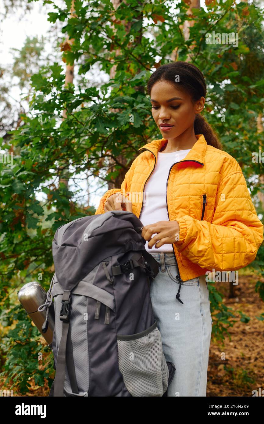 A young woman adjusts her backpack in a colorful autumn forest, ready ...