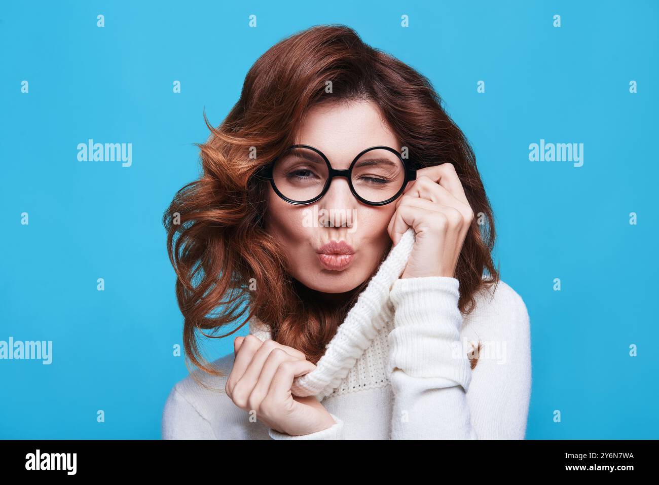 Flirty beauty. Attractive young woman winking and kissing while ...