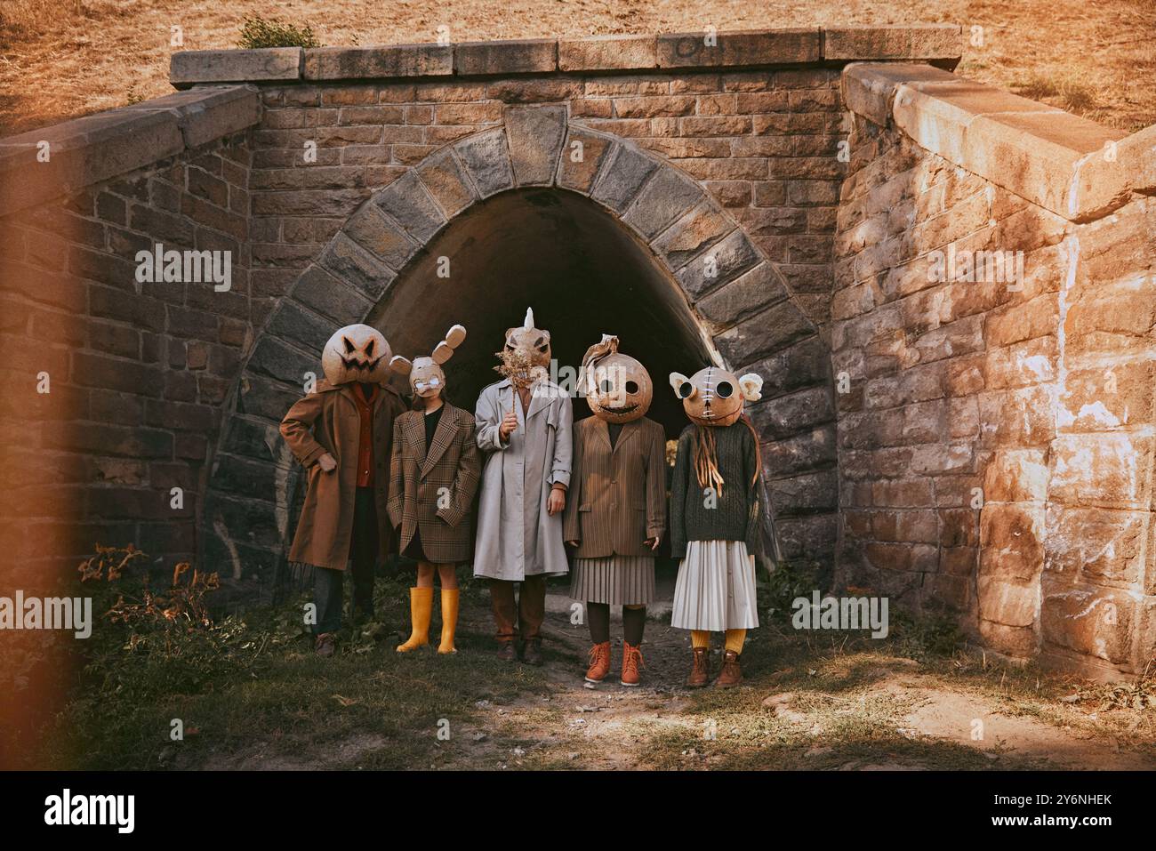 Five eerie figures with bizarre, handmade masks standing under stone ...