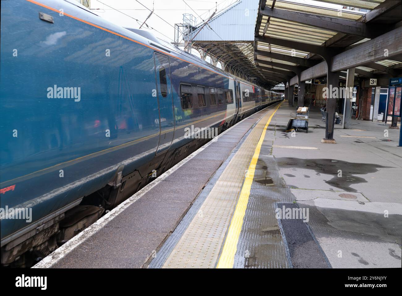 Empty platform at a train station with a stationary train, reflecting ...