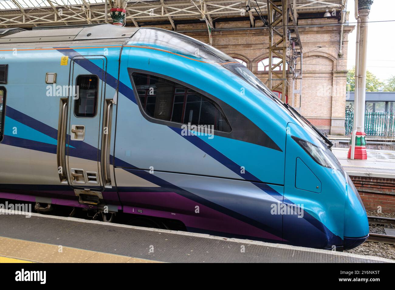 Sleek blue and purple train paused at a station, showcasing contemporary public transport design ...