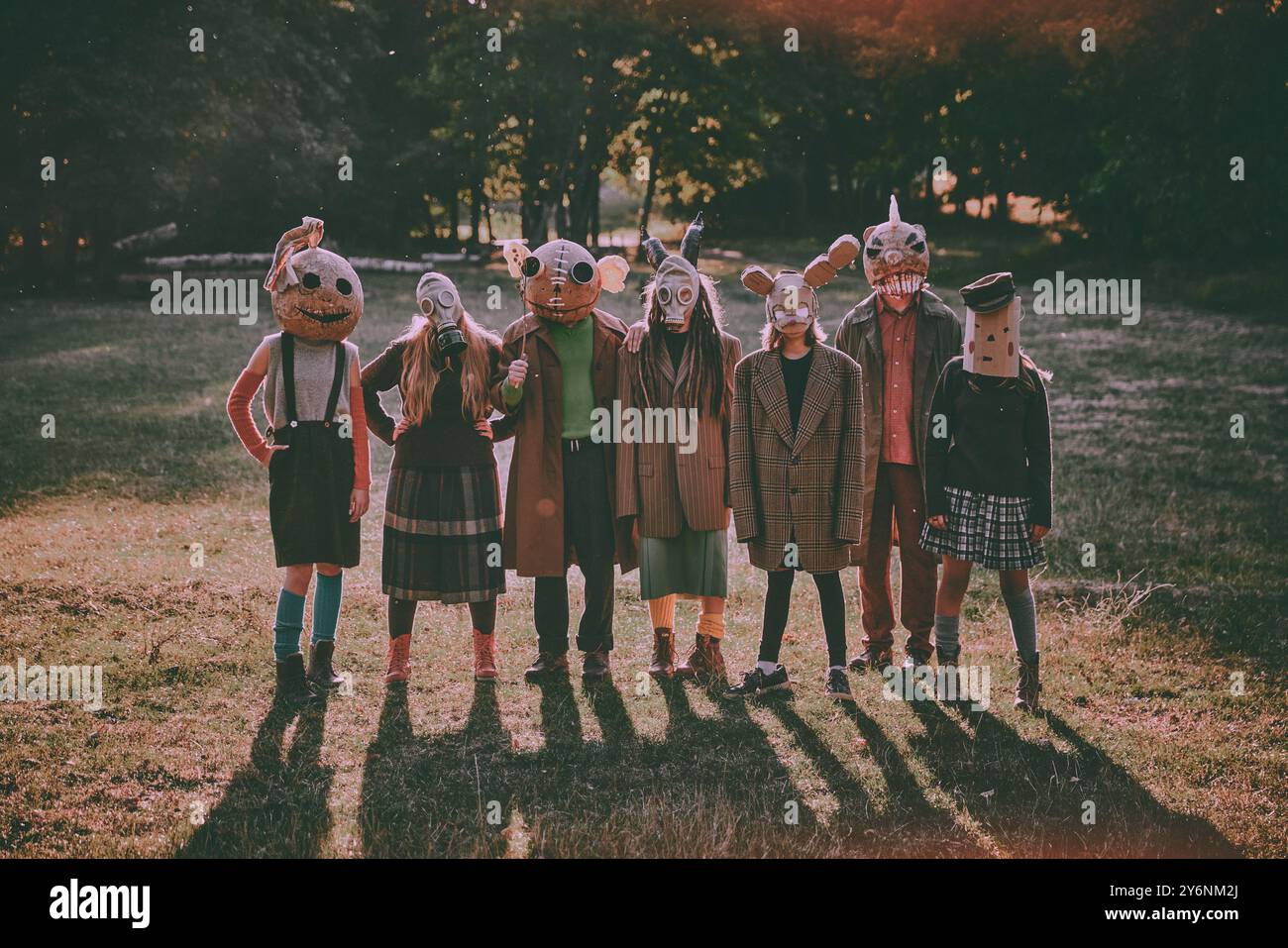 Group of people in creepy masks and odd clothes standing in autumn ...