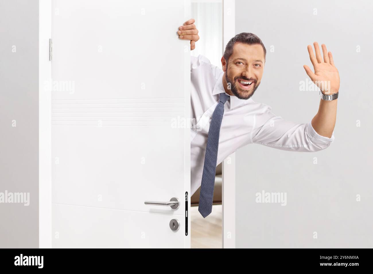 Cheerful man opening a door and waving Stock Photo - Alamy