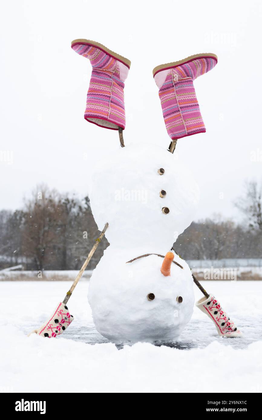 funny snowman in boots stands upside down in the snow. Fun holiday in ...