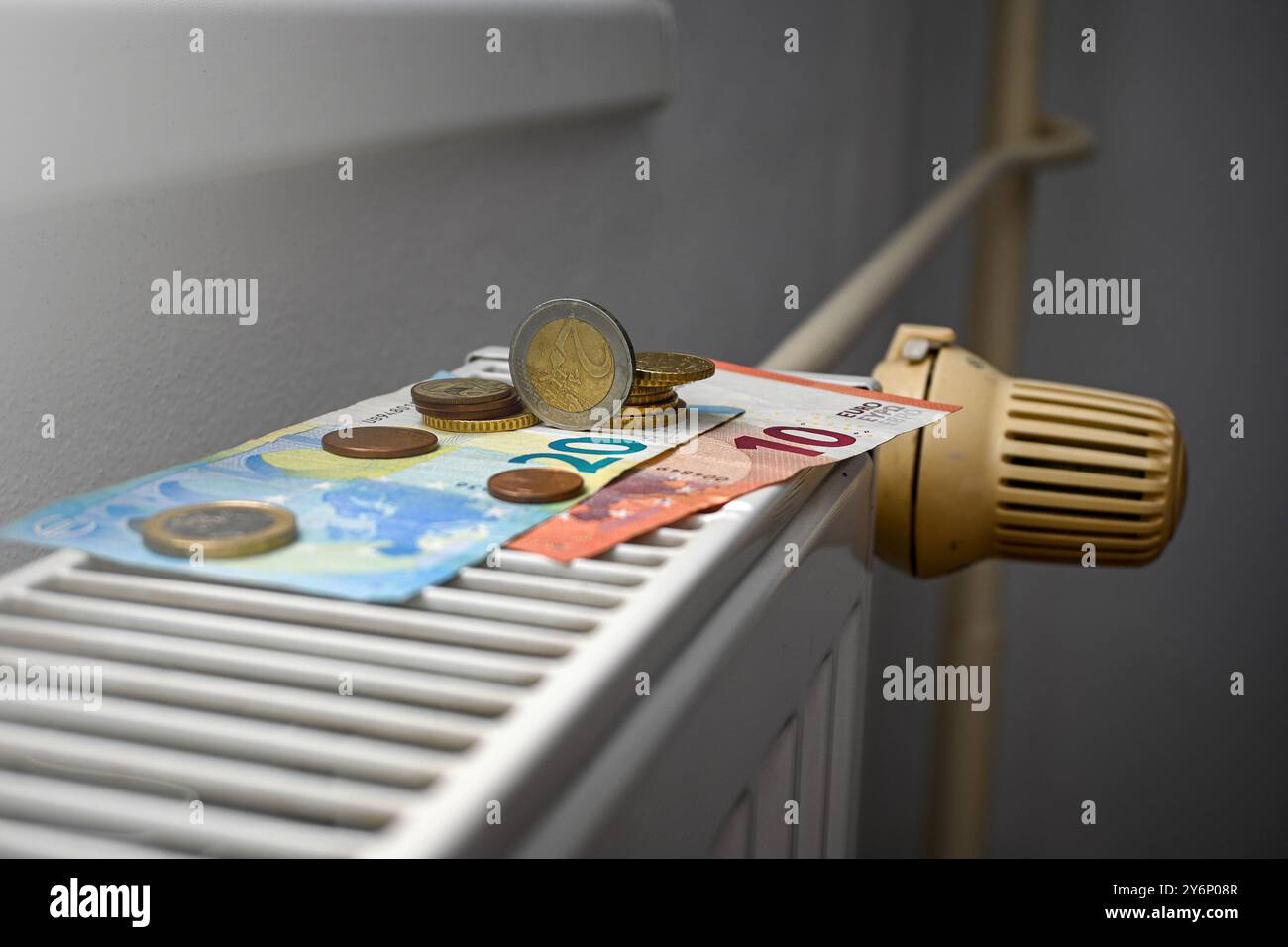 Euro banknotes and coins are sitting on a radiator, illustrating the ...
