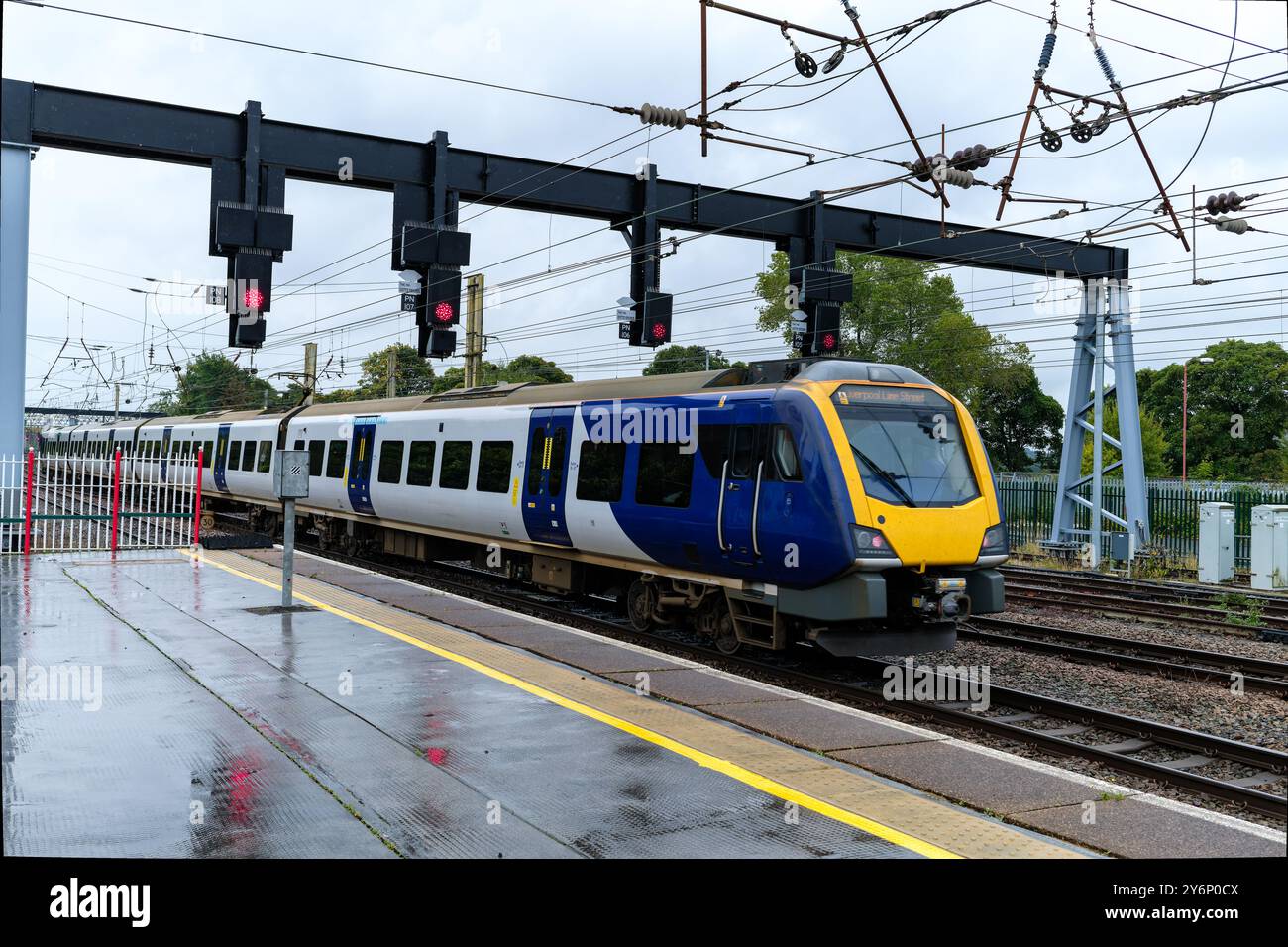 Electric passenger train arriving at a wet platform, showcasing modern ...