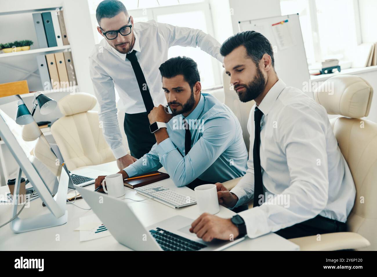 Inspired to work hard. Group of young modern men in formalwear working ...
