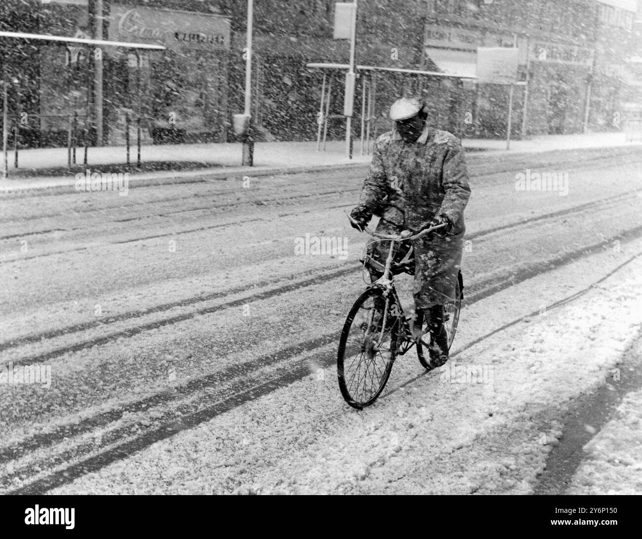Weather conditions/Winter snow. A man rides a push bike on the road ...