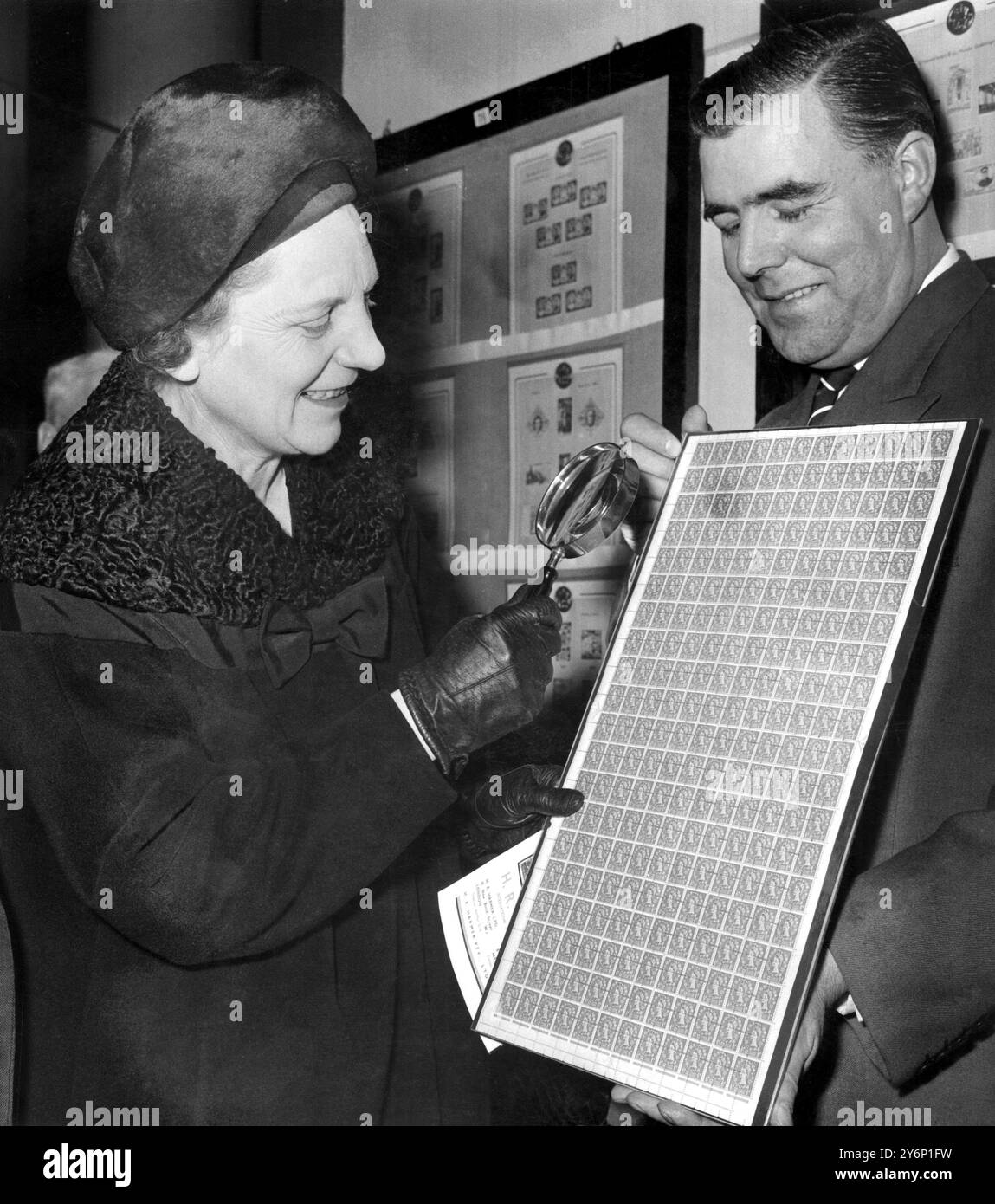 With a magnifying glass, Miss Mervyn Pike, Assistant Postmaster General ...