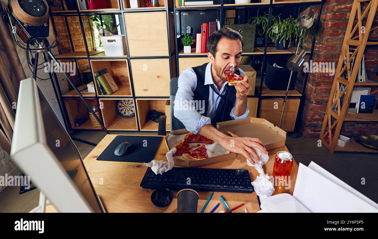 Businessman eating pizza while working. He wearing formal attire, but ...