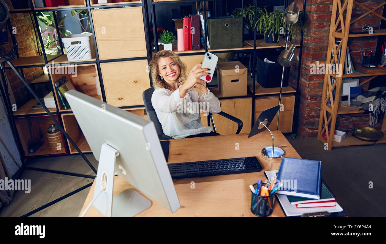 Woman takes selfie at her desk, completely distracted from her tasks ...