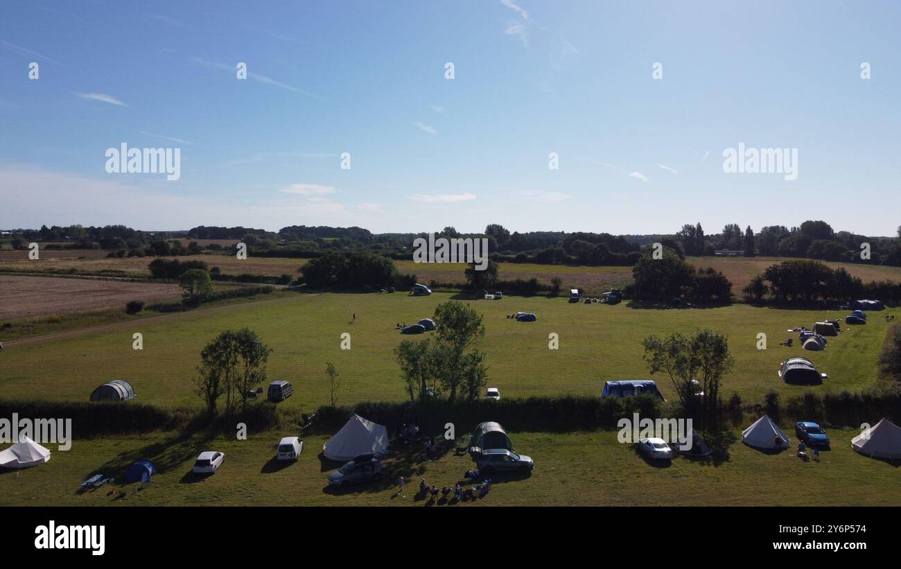 Aerial view of a countryside campsite with scattered tents and vehicles ...